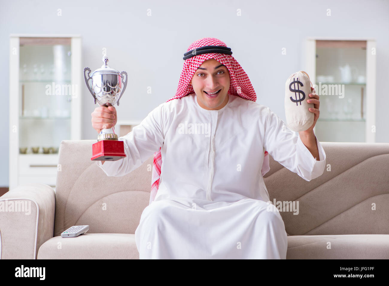 Arab man with prize and money on sofa Stock Photo - Alamy