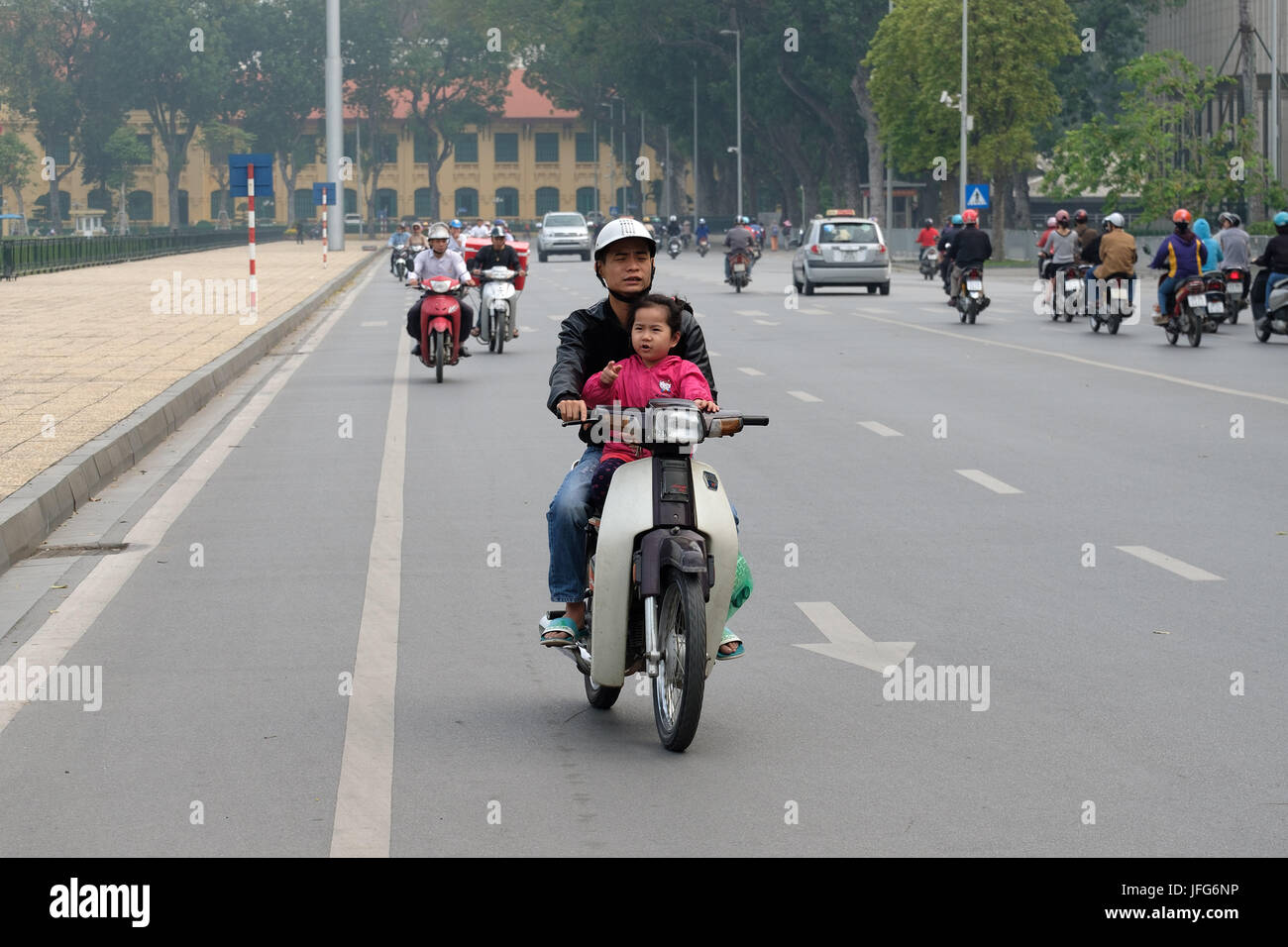 Man riding motor scooters with a young child on the streets of Hanoi ...