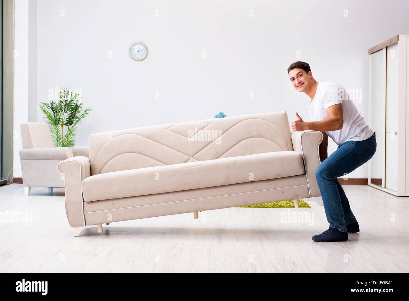 Young man moving furniture at home Stock Photo - Alamy