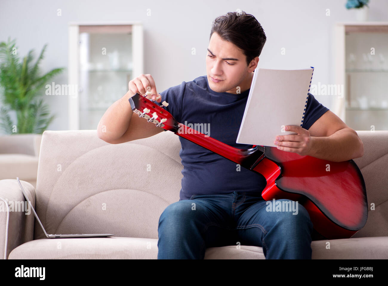 Young man practicing playing guitar at home Stock Photo - Alamy
