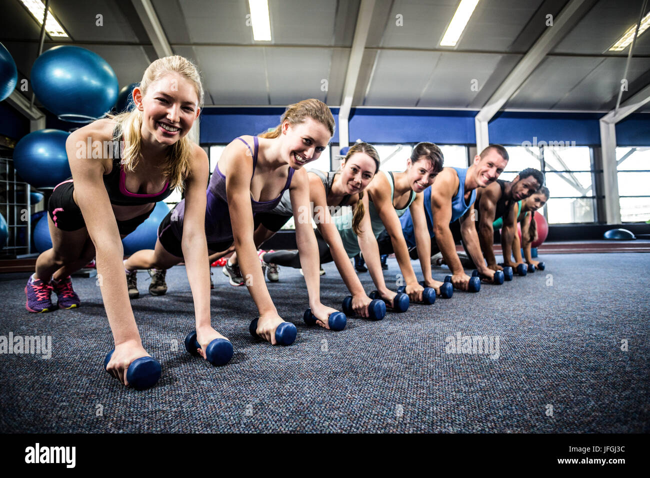 Fitness class in plank position with dumbbells Stock Photo - Alamy