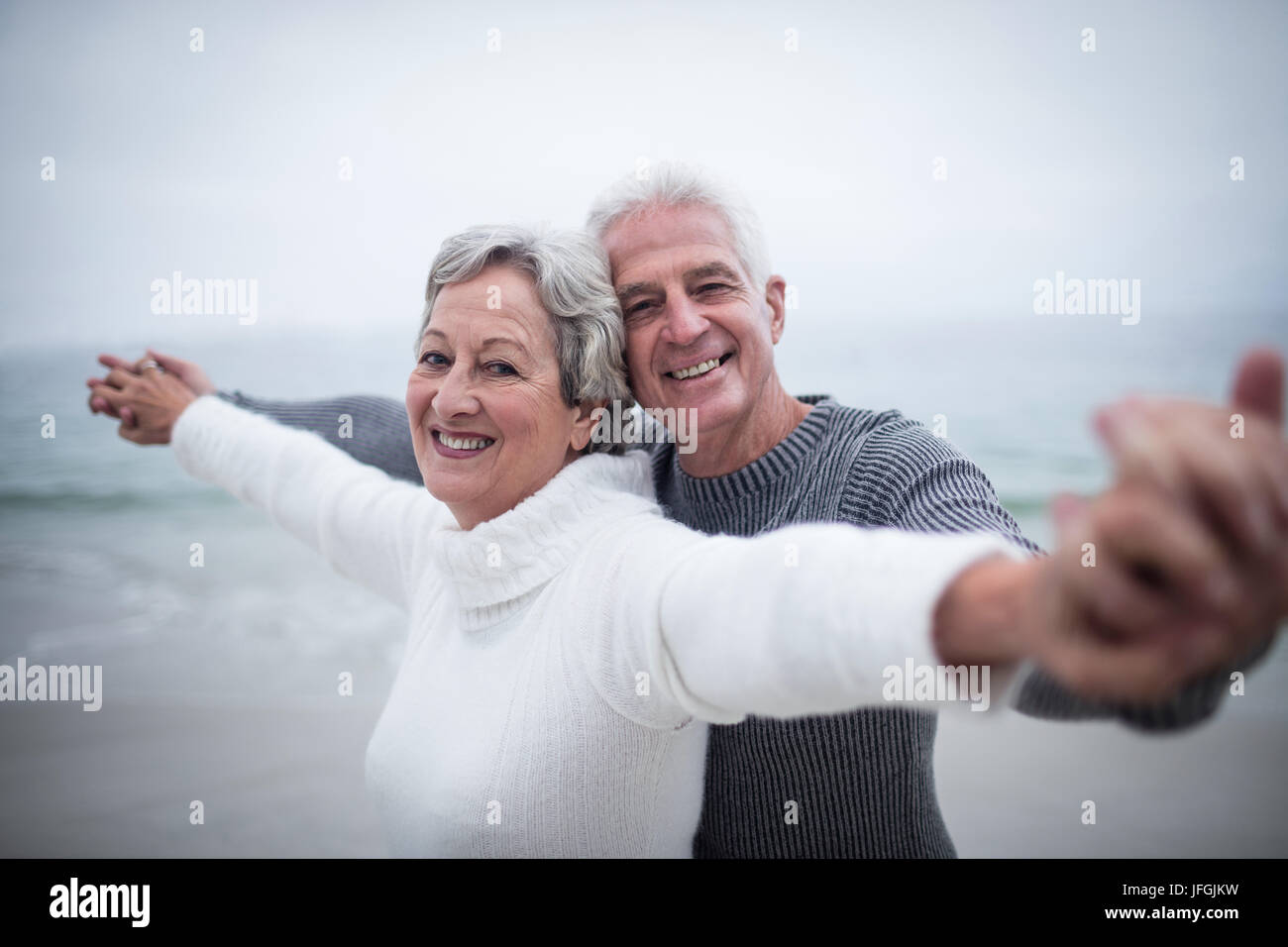 Portrait of happy senior couple standing with arms outstretched Stock ...