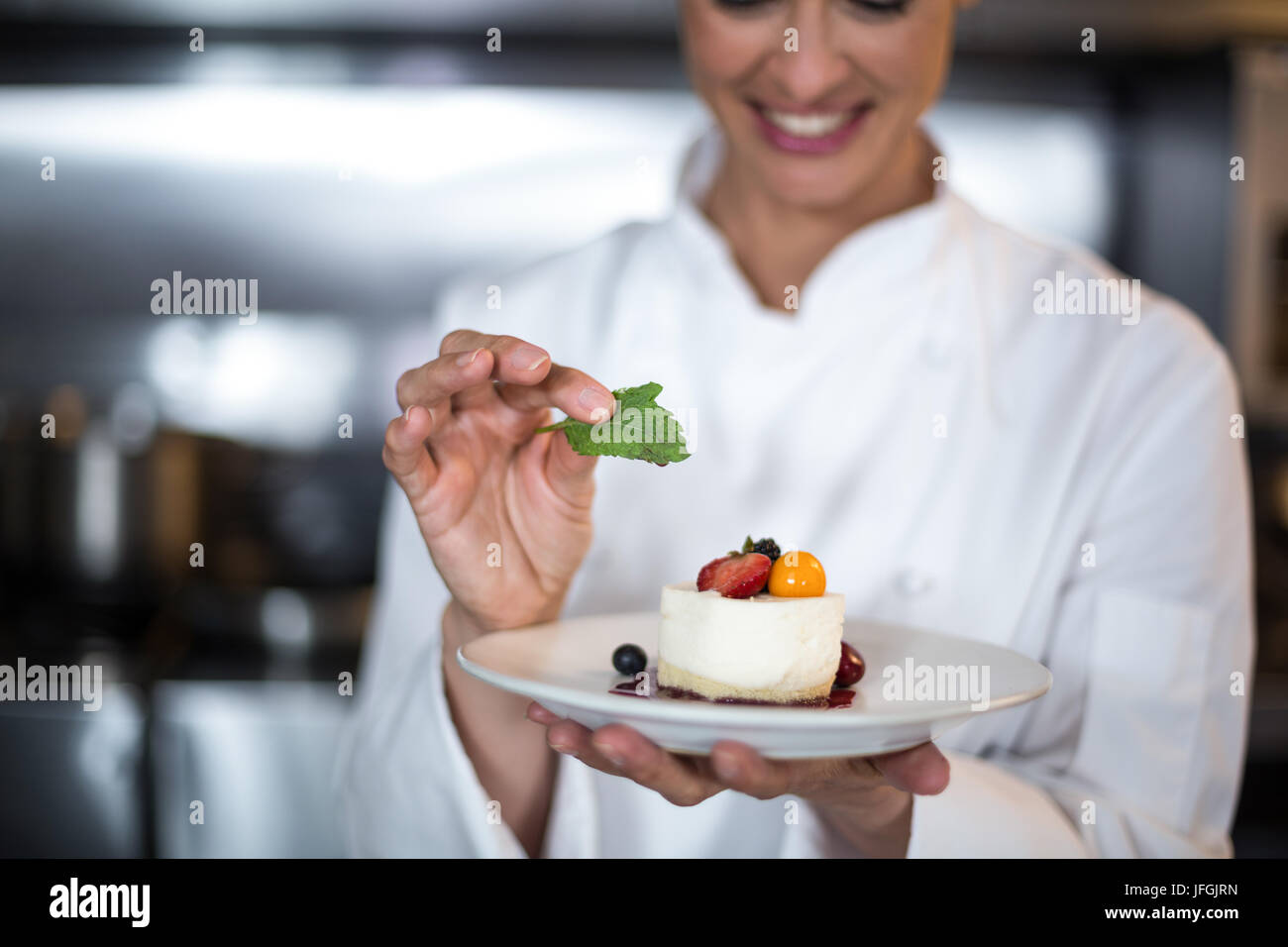 Smiling female chef holding food plate in kitchen Stock Photo - Alamy