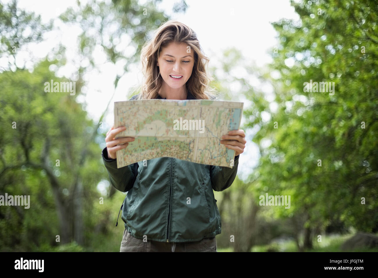 Young woman looking at map while standing in forest Stock Photo - Alamy