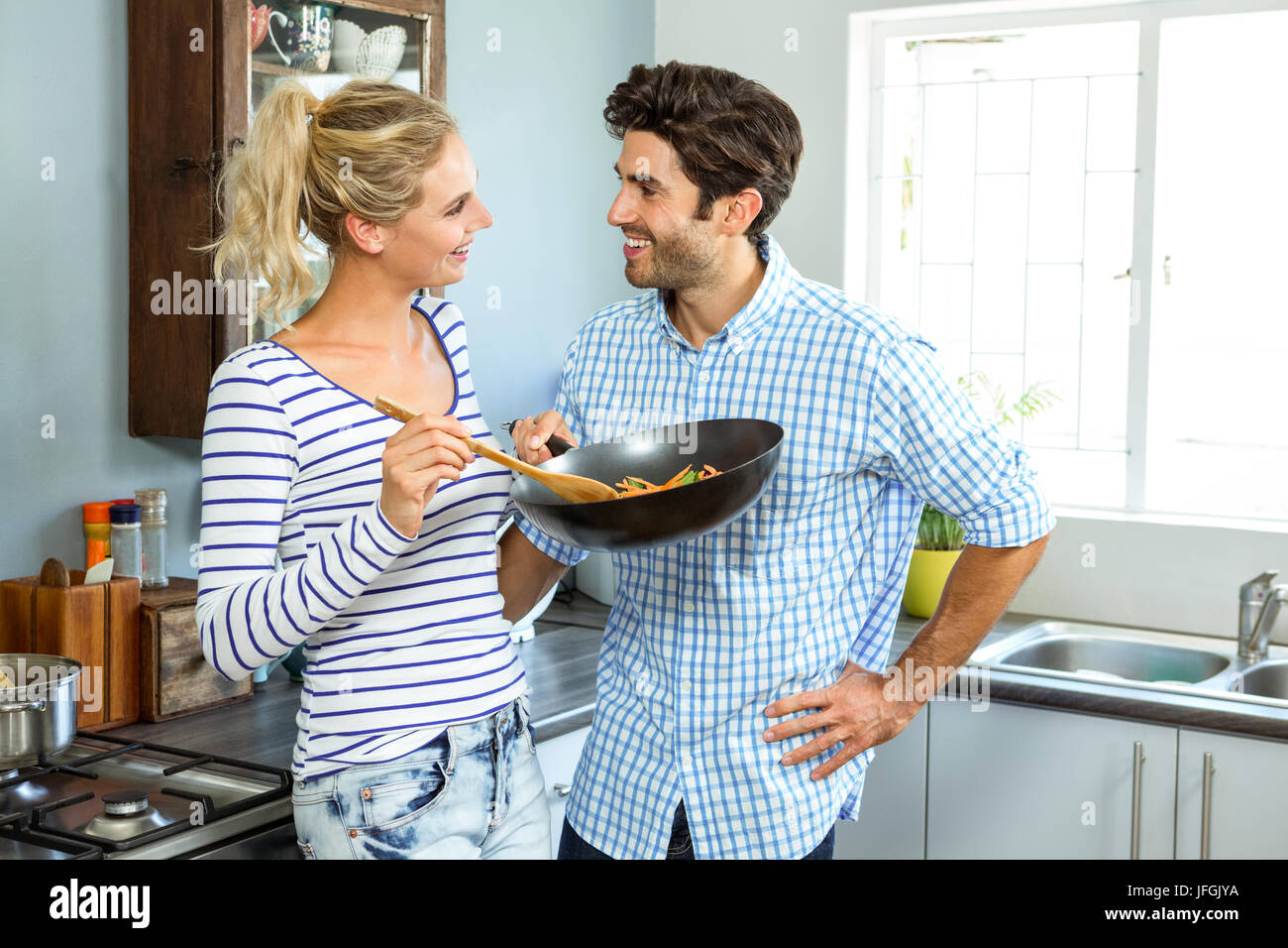 Young couple preparing food together in kitchen Stock Photo - Alamy