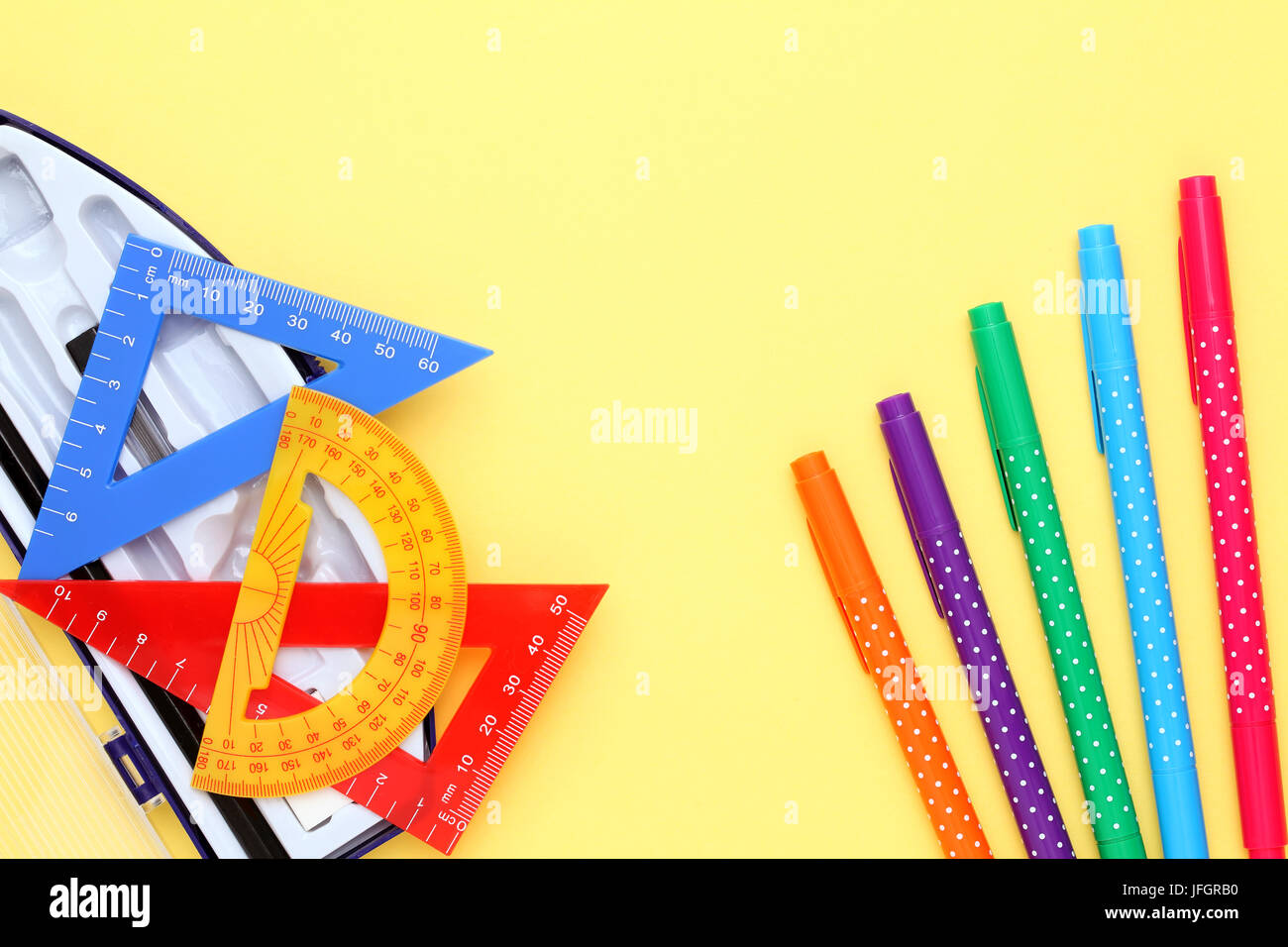 Multicolored rulers and pen on yellow background Stock Photo - Alamy