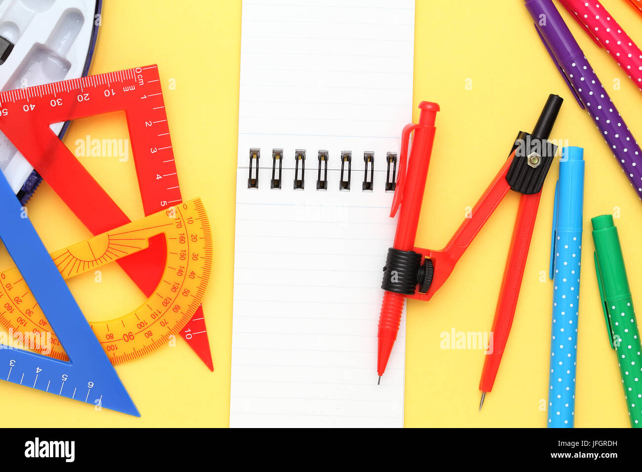 Multicolored pen, rulers and notebook on yellow background Stock Photo ...