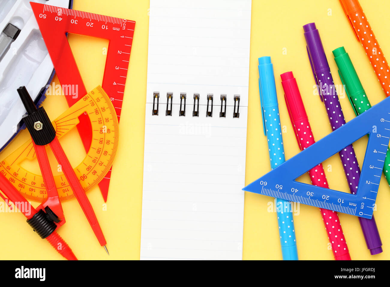 Multicolored pen, rulers and notebook on yellow background Stock Photo ...