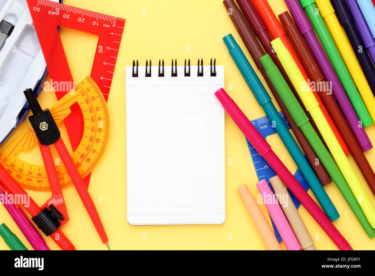 Multicolored pen, rulers and notebook on yellow background Stock Photo ...