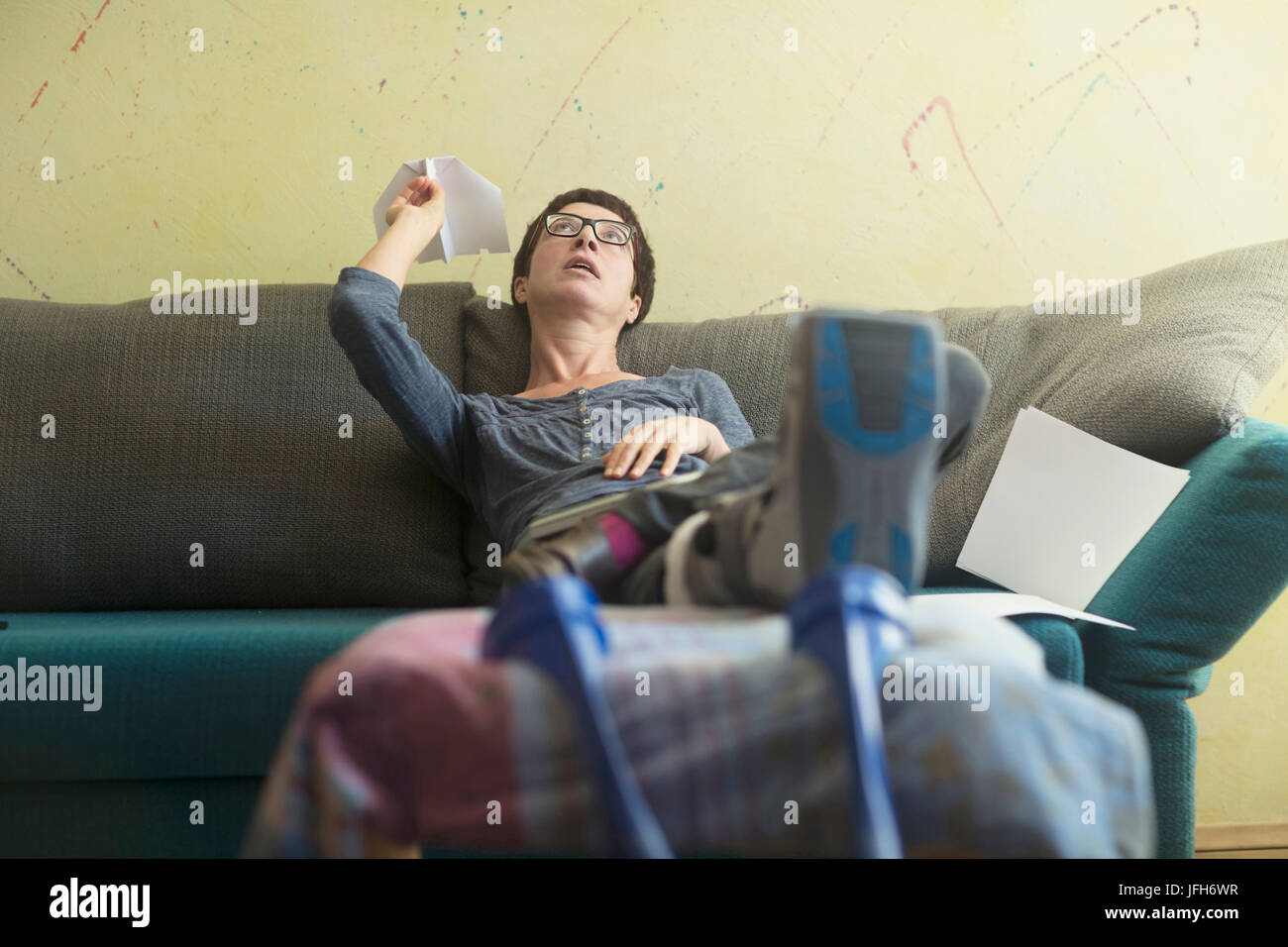 Woman with broken leg lying on sofa and throwing paper aeroplane Stock ...