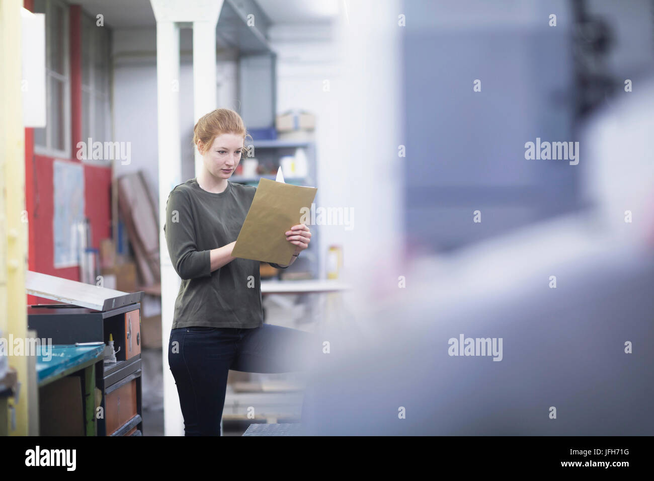 Woman reading paper at printing press Stock Photo - Alamy