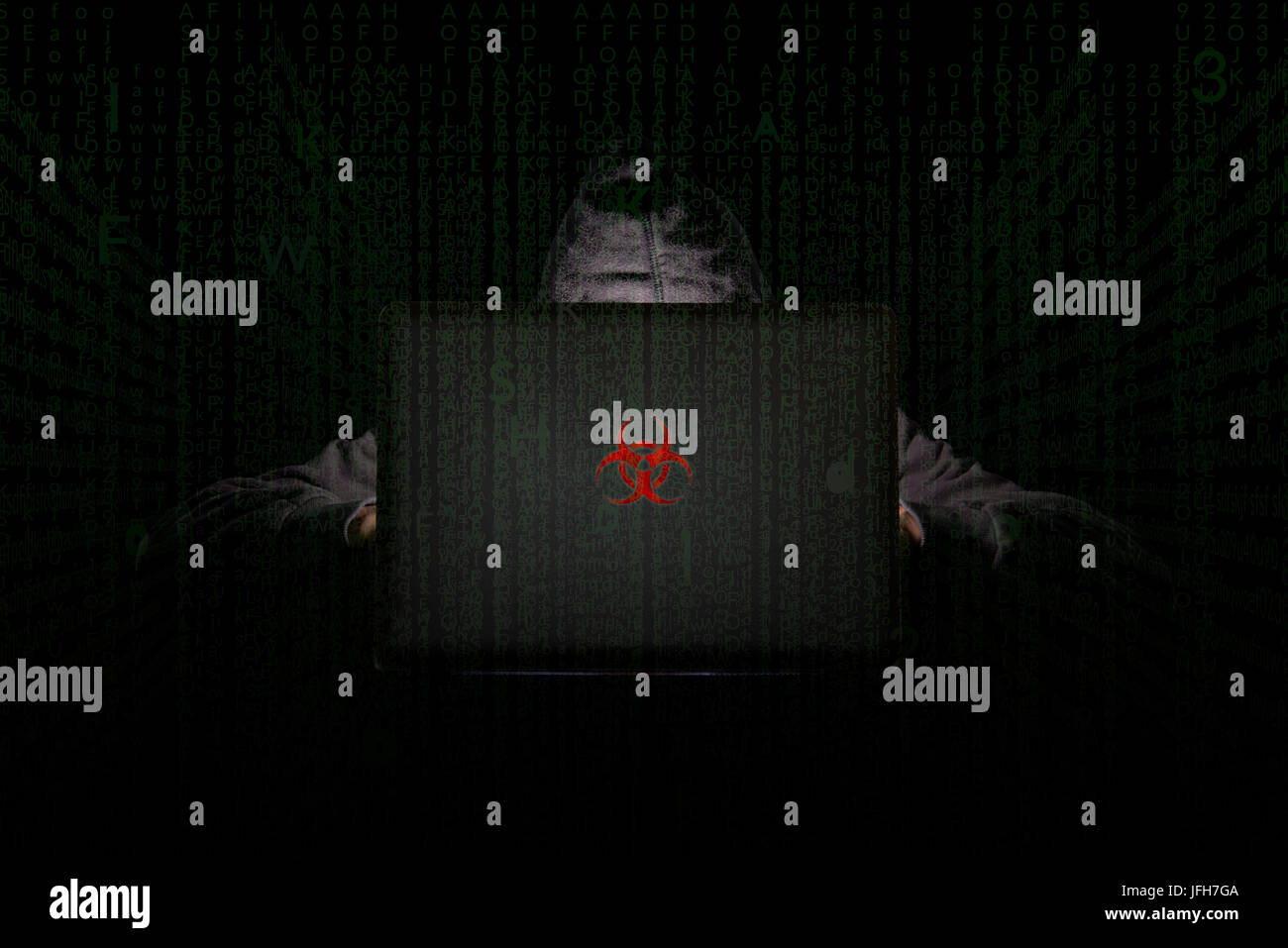 Hacker in a dark room using a laptop with a red biohazard logo ...