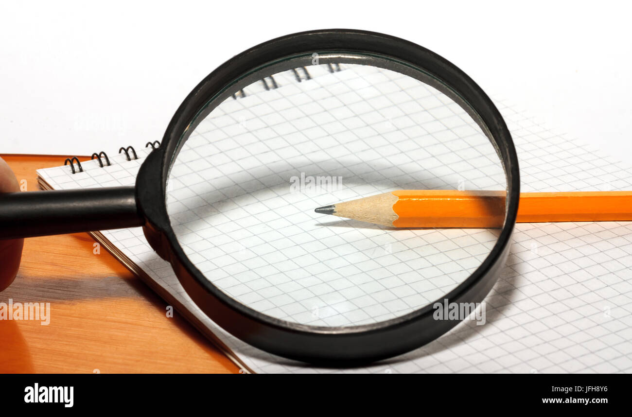 Pencil and magnifier on a notebook Stock Photo - Alamy