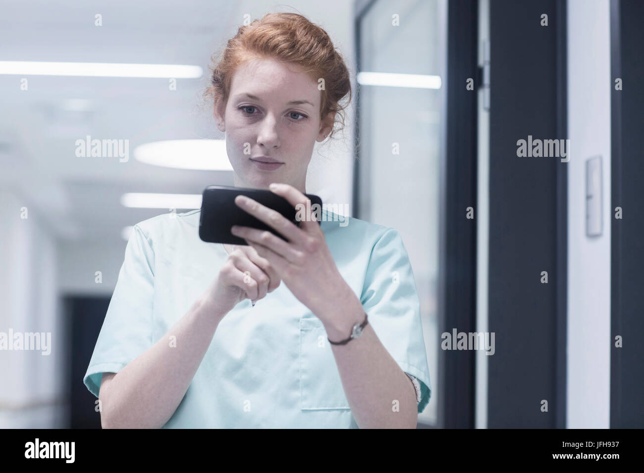 Young female nurse using mobile phone in hospital Stock Photo - Alamy