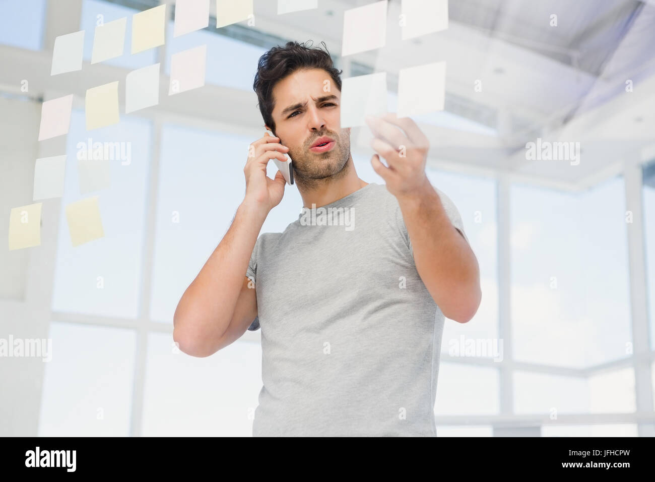 Man looking at a sticky notes while talking on phone Stock Photo - Alamy