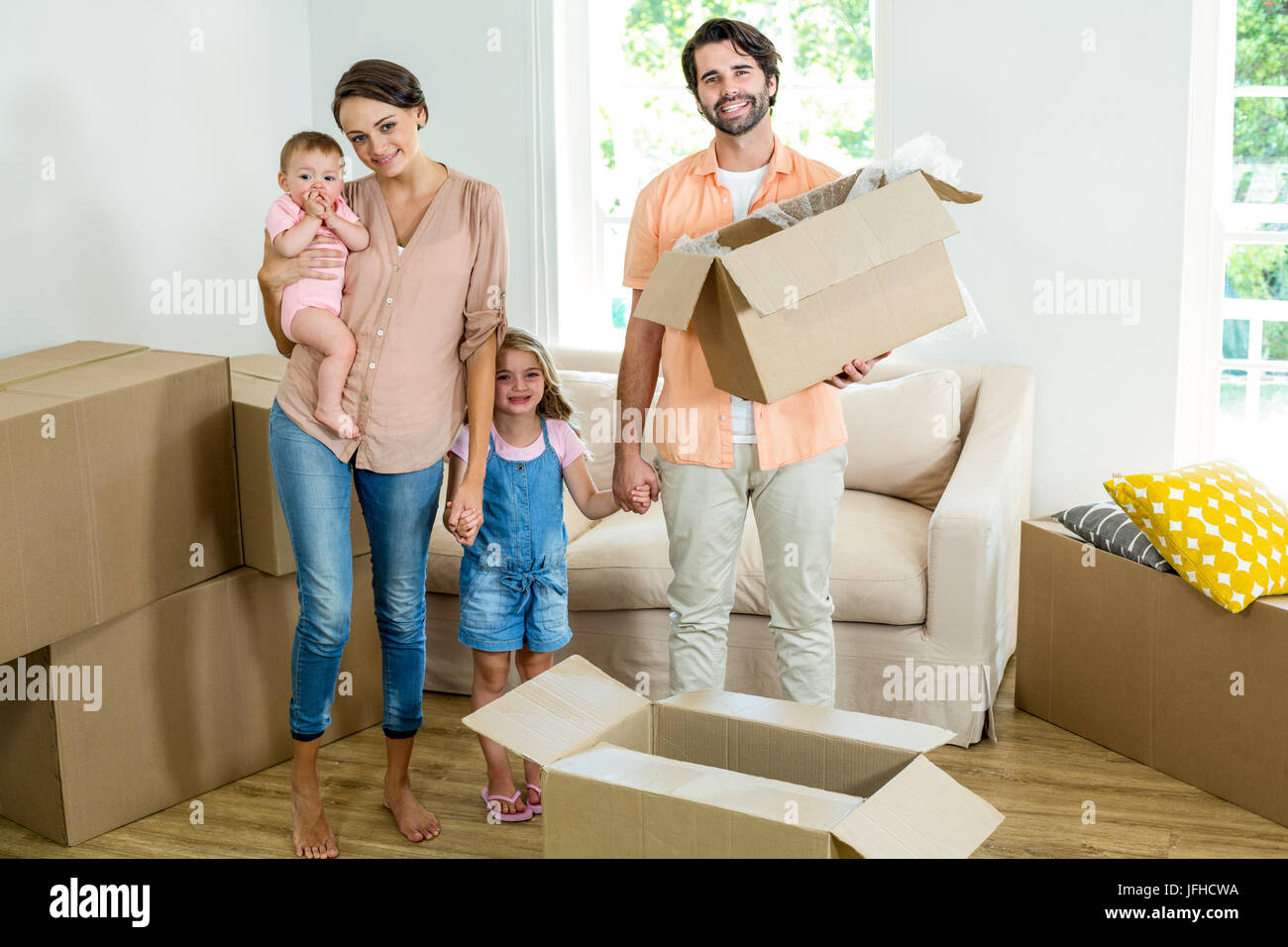Happy family standing with boxes in new house Stock Photo - Alamy
