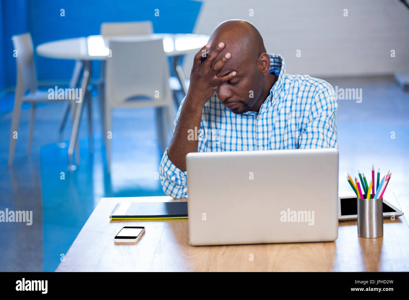 Tense man sitting on table with laptop and graphics tablet Stock Photo ...