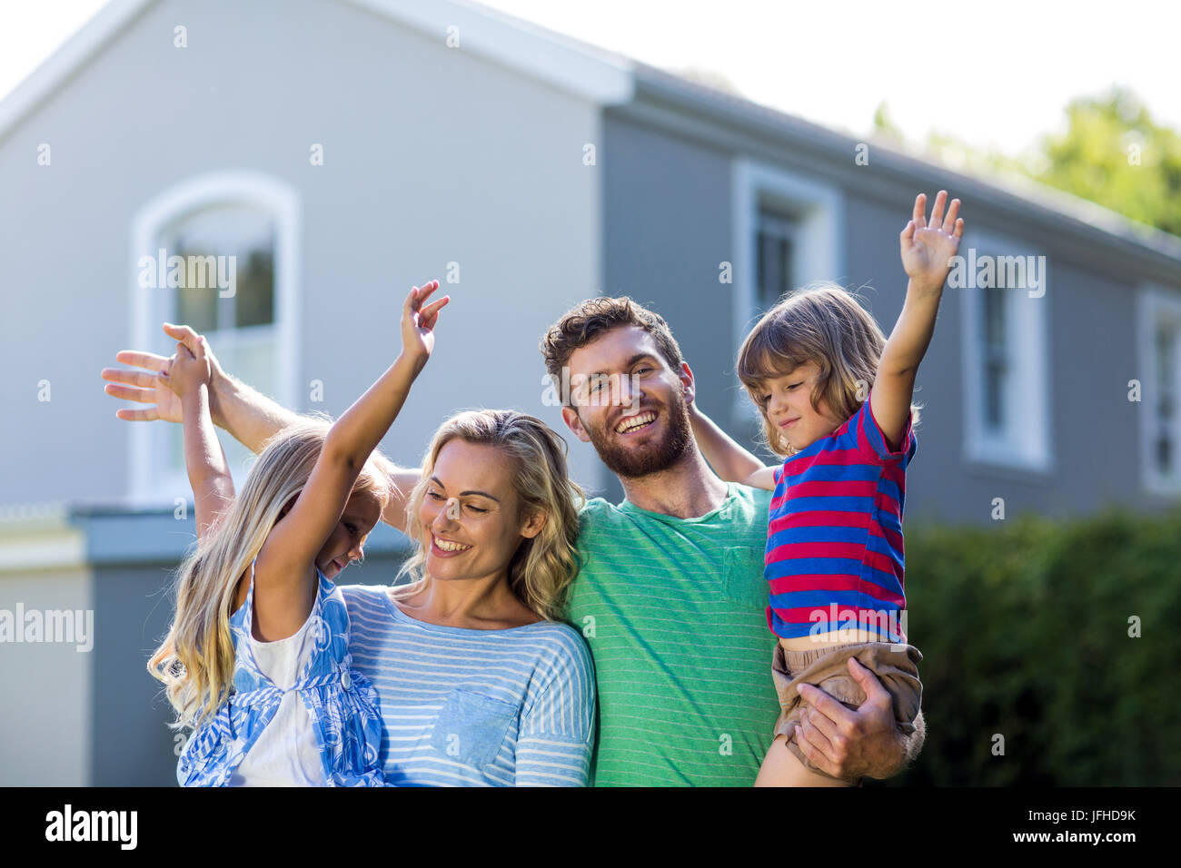 Happy parents carrying children with arms raised Stock Photo - Alamy