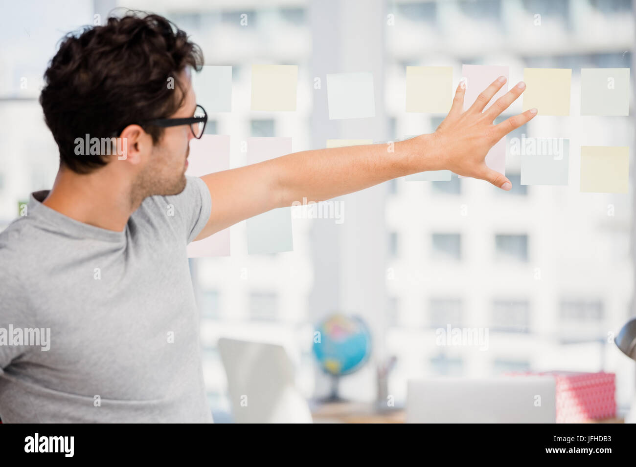 Thoughtful man looking at sticky notes on window Stock Photo - Alamy