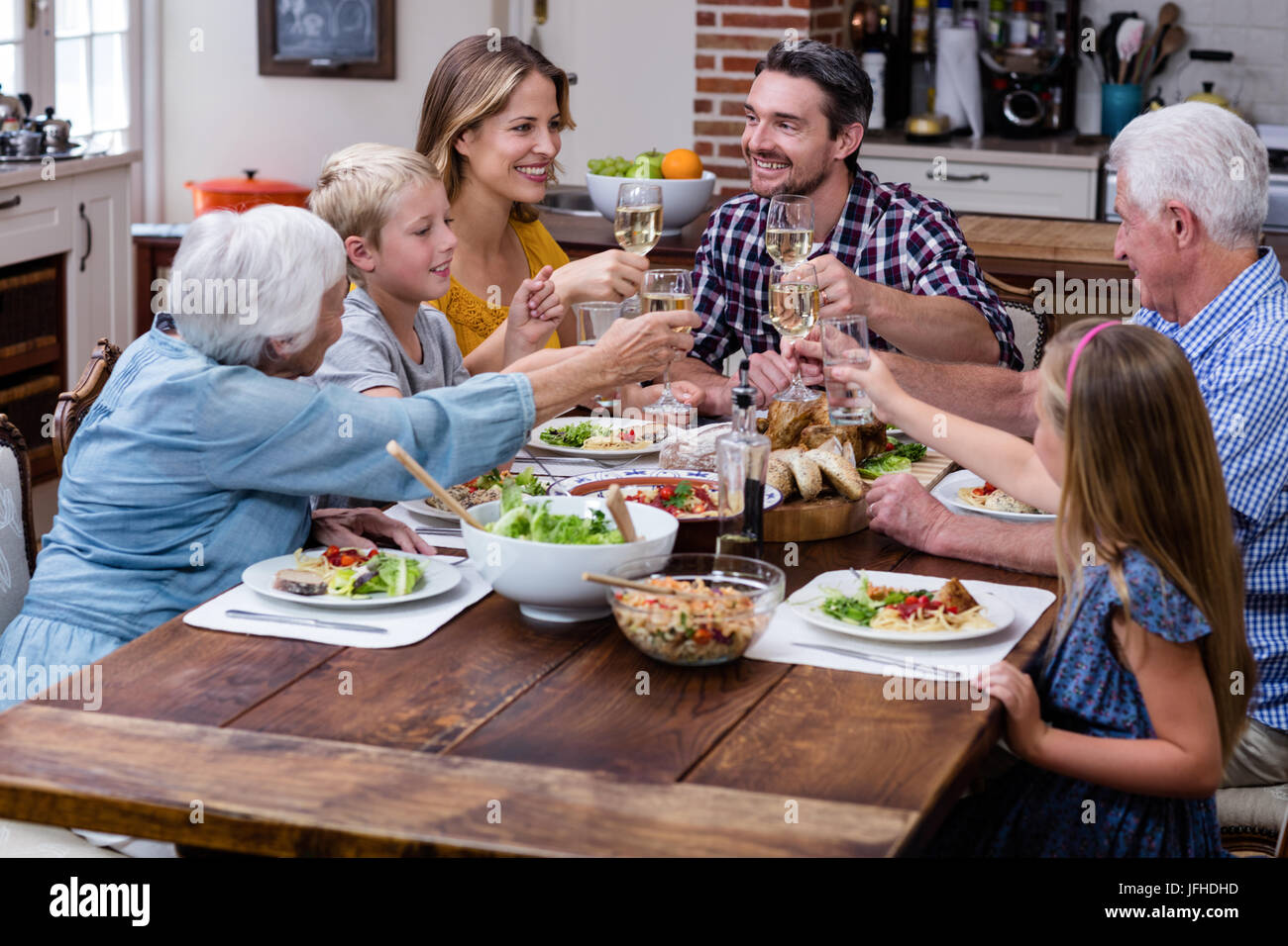 Multi-generation family toasting glass of wine while having meal Stock ...