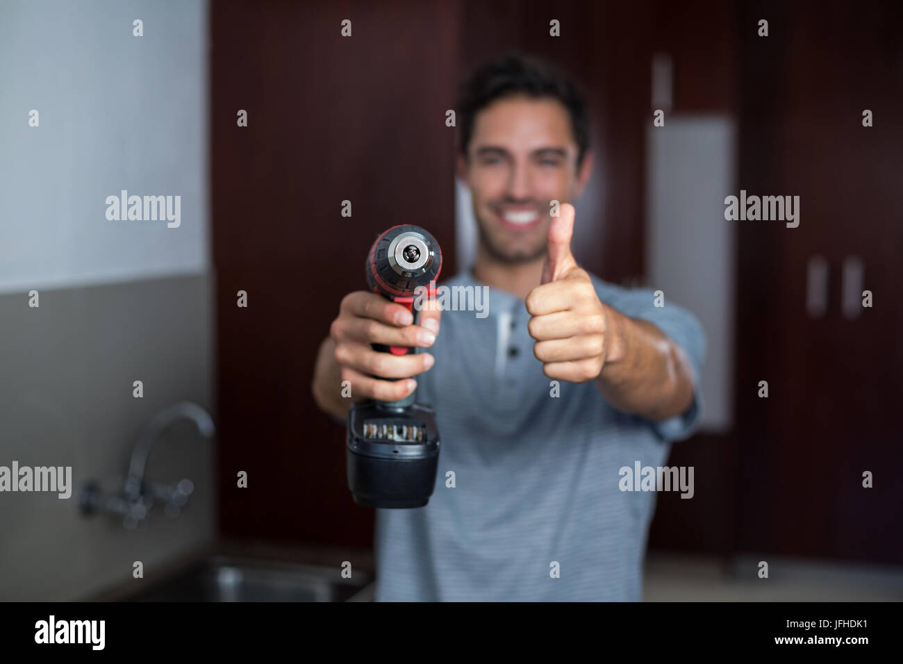 Smiling man showing thumbs up while holding cordless hand drill Stock ...