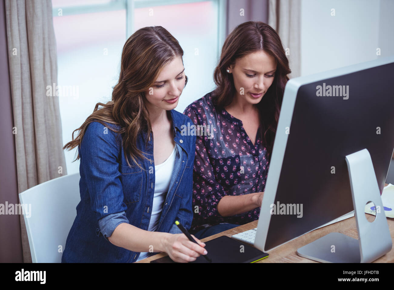 Two beautiful woman using computer and pen tablet Stock Photo - Alamy