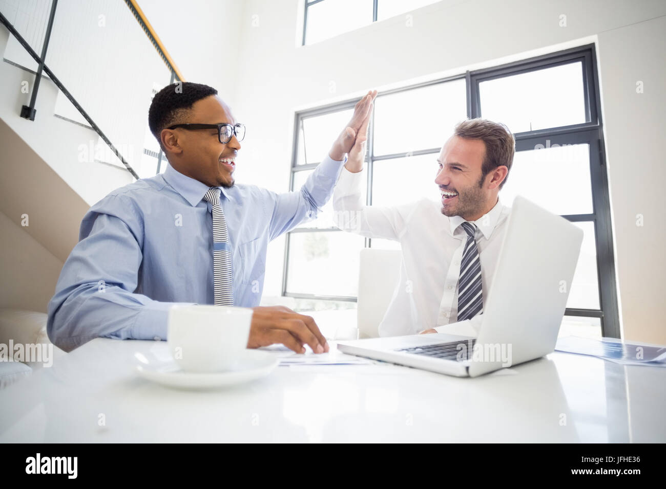 Businessmen giving a high five while at a meeting Stock Photo - Alamy