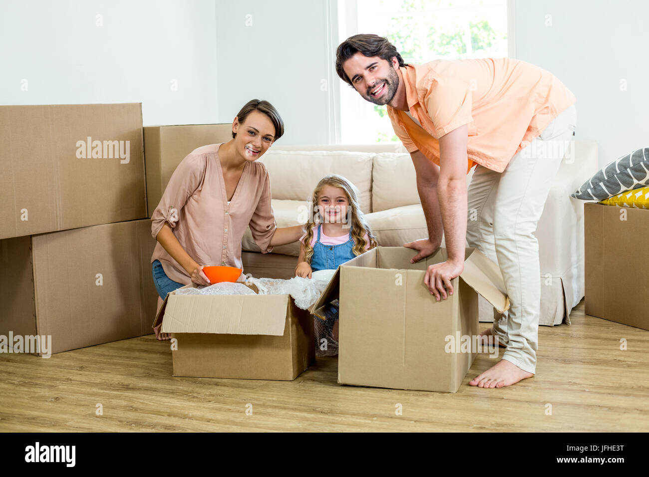 Family unpacking boxes while relocating in new house Stock Photo - Alamy