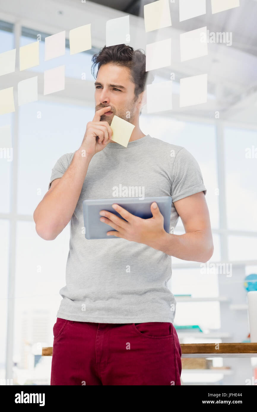 Thoughtful man holding digital tablet and sticky notes Stock Photo - Alamy