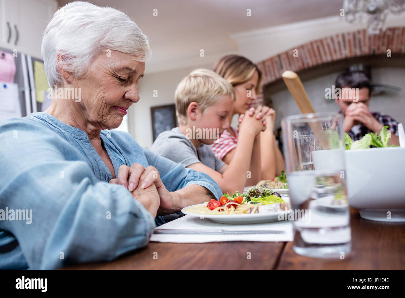 Multi-generation family praying before having meal Stock Photo - Alamy