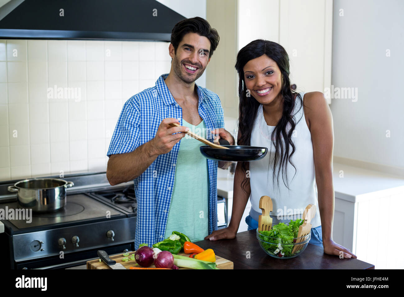 Portrait of young couple cooking food together in kitchen Stock Photo ...