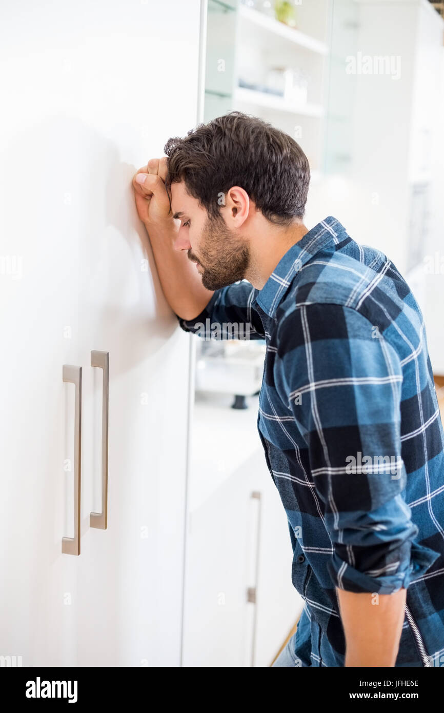 Depressed man leaning his head against a door Stock Photo - Alamy