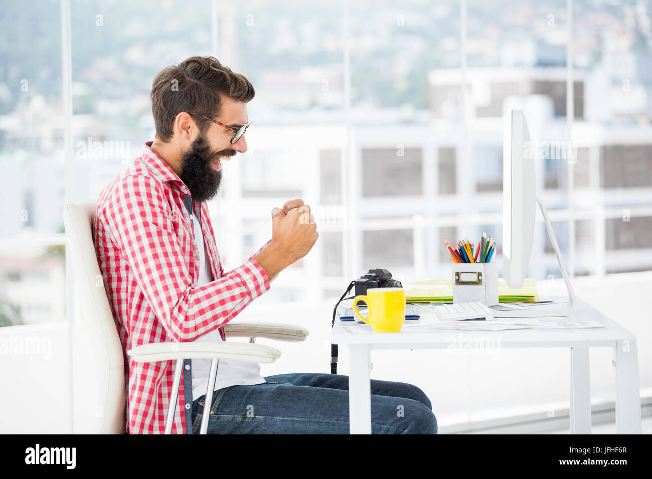 Hipster man sitting at computer desk is happy Stock Photo - Alamy