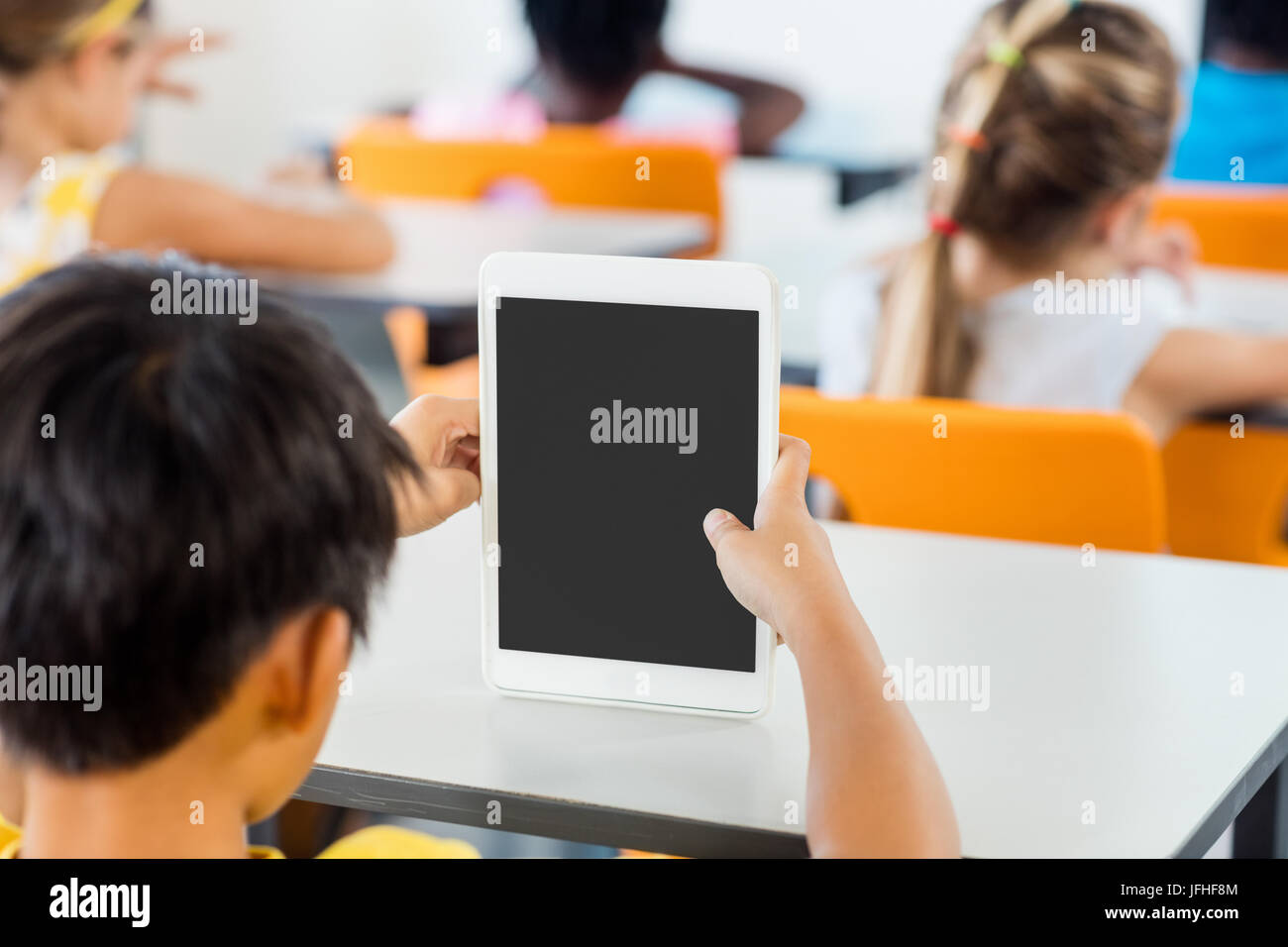 Rear view of pupils using tablet pc in classroom Stock Photo - Alamy