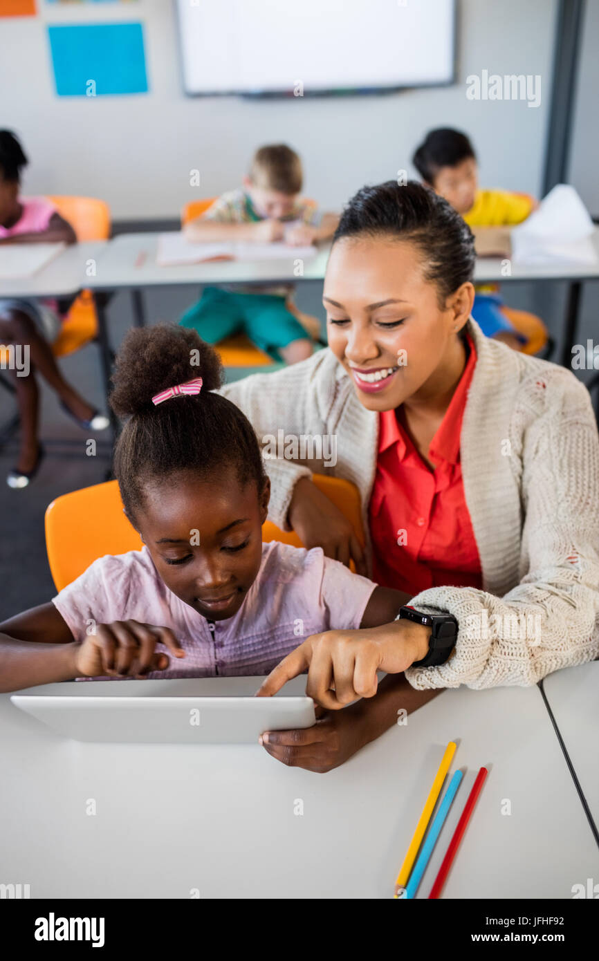 School girl using tablet at desk with her teacher Stock Photo - Alamy