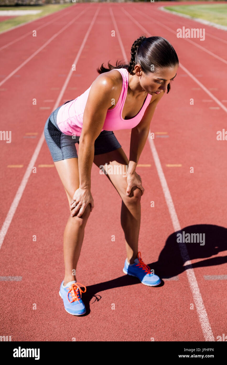 Tired female athlete standing on running track Stock Photo - Alamy