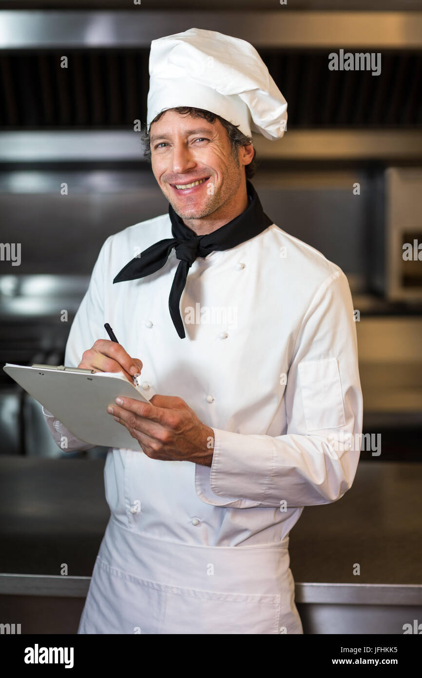 Portrait of happy chef writing on clipboard in kitchen Stock Photo - Alamy