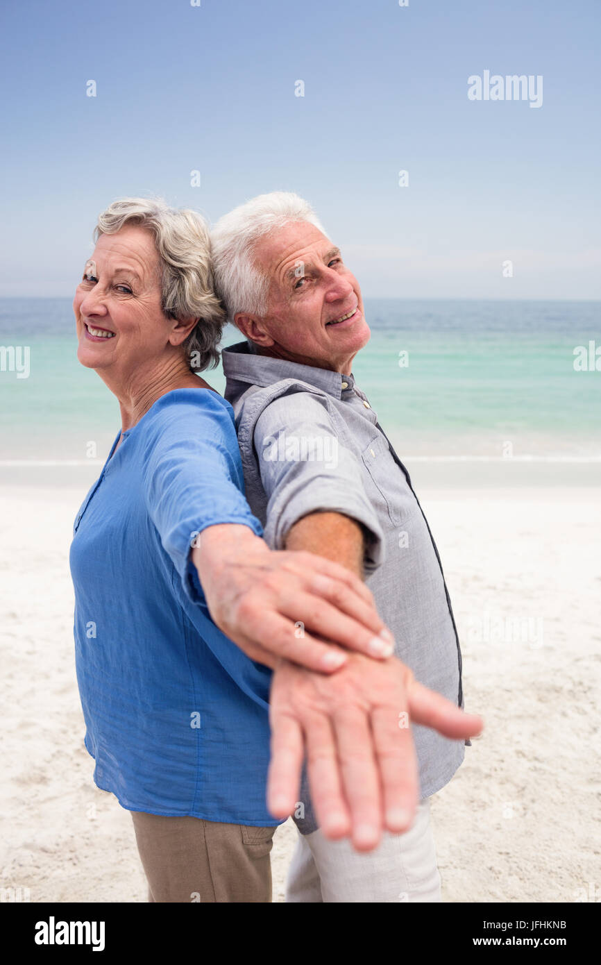 Senior couple standing back to back with arms outstretched Stock Photo ...