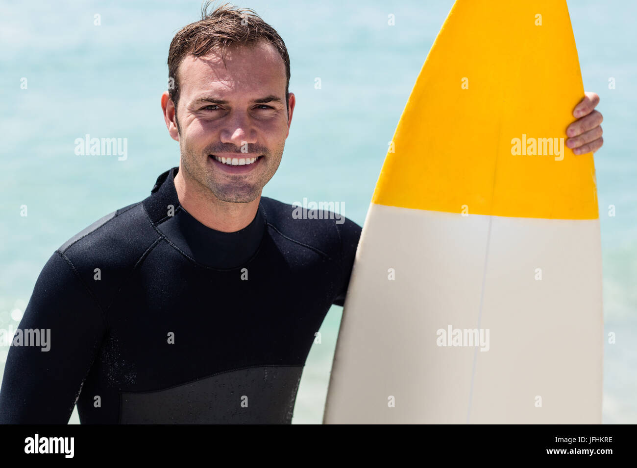 Happy surfer holding a surfboard on the beach Stock Photo - Alamy