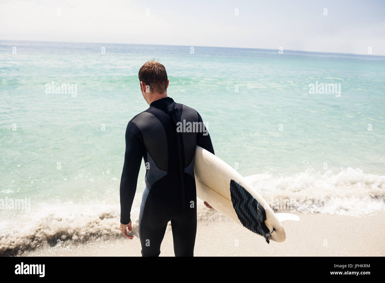 Rear view of surfer holding surfboard on beach Stock Photo - Alamy