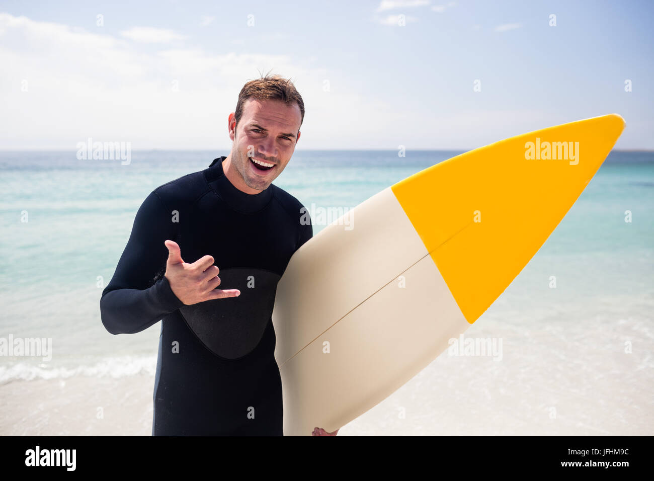 Surfer with surfboard gesturing hand sign on beach Stock Photo - Alamy