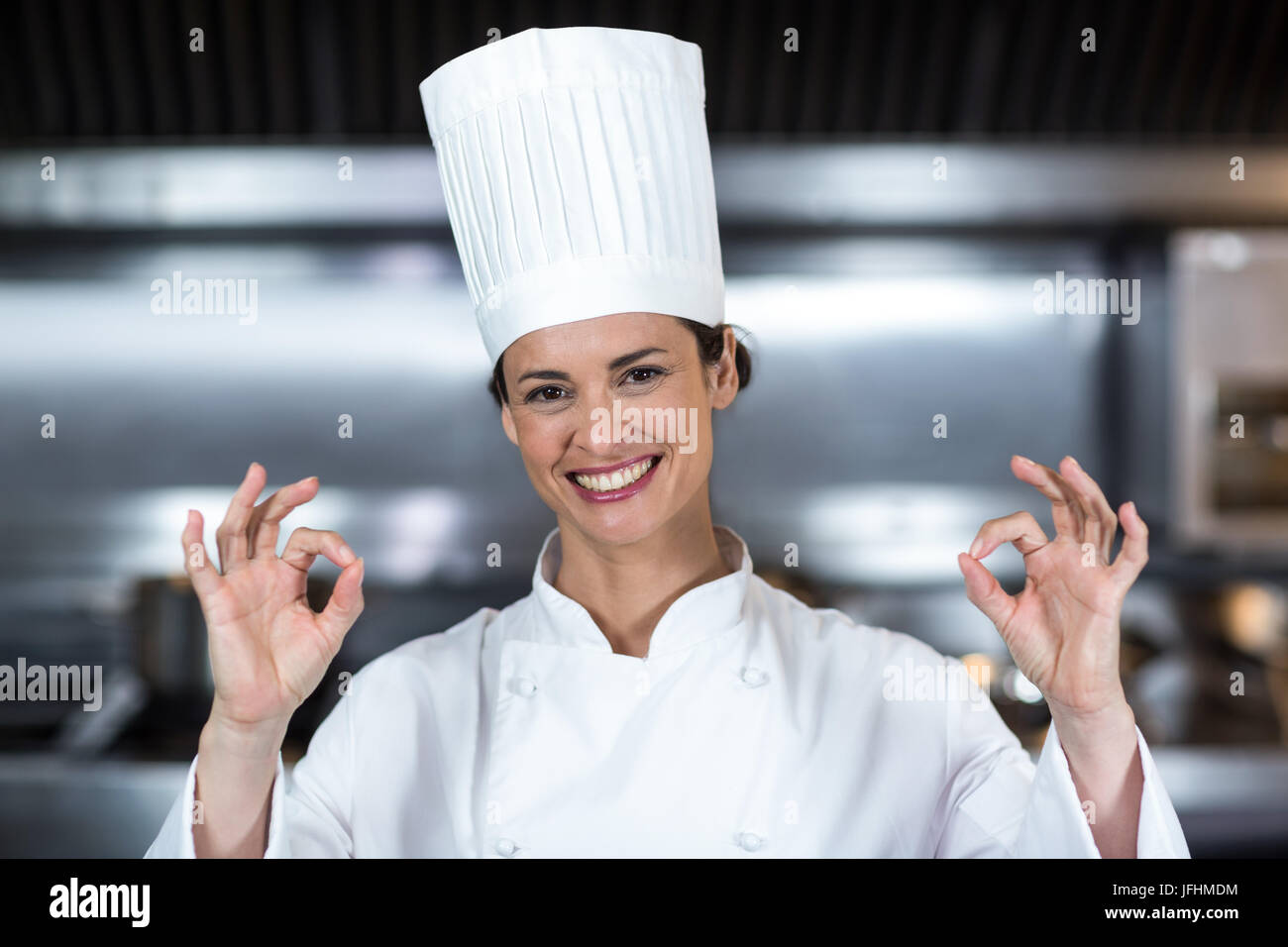 Portrait of happy female chef showing ok sign in kitchen Stock Photo ...