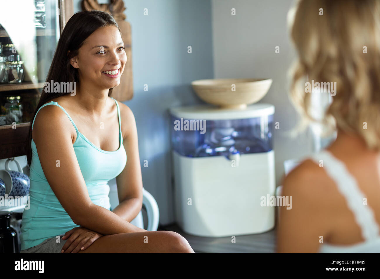 Smiling woman talking with female friend at home Stock Photo - Alamy