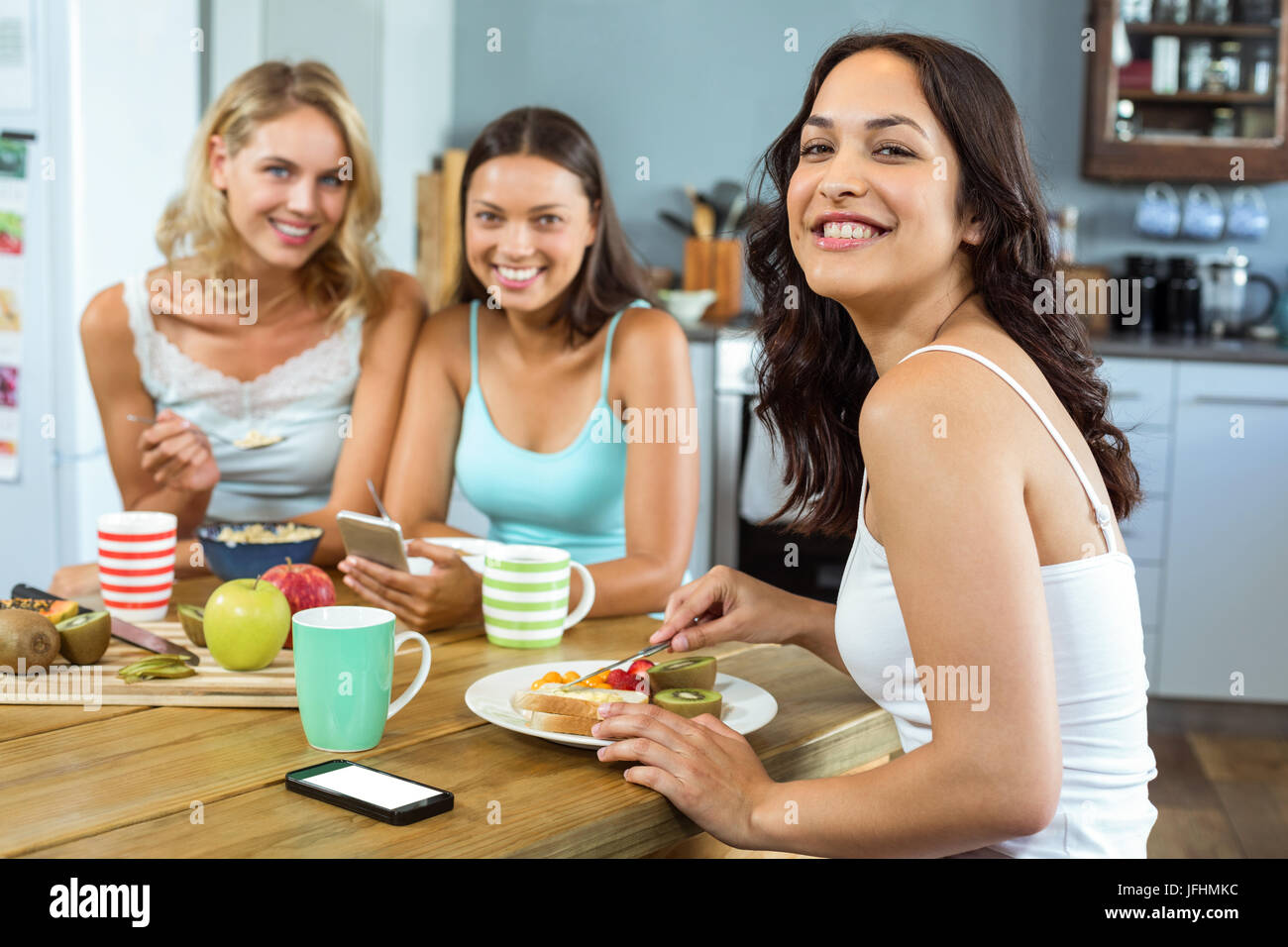 Happy friends having breakfast at table in house Stock Photo - Alamy