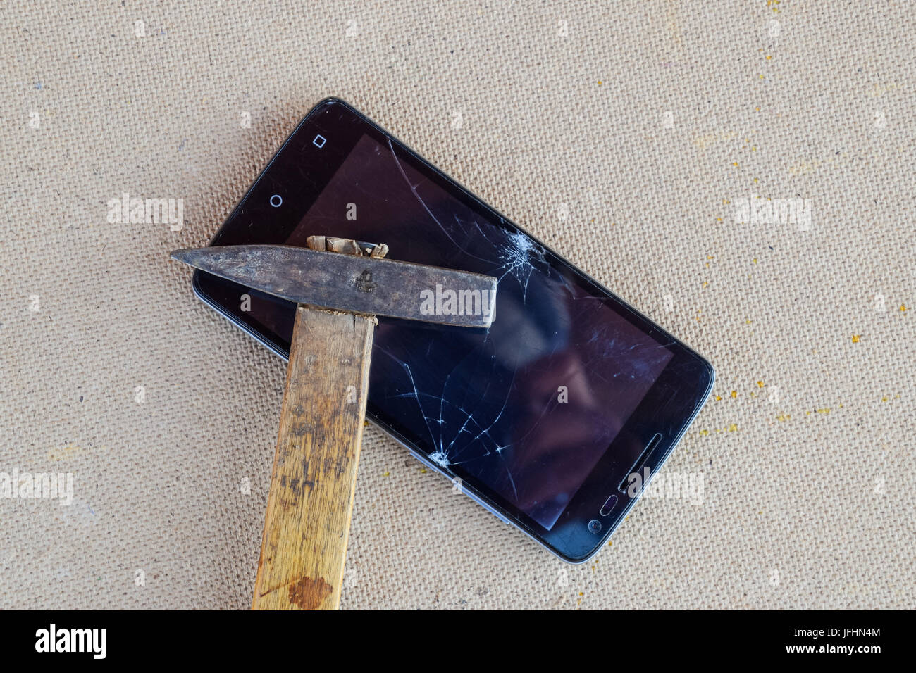 Hammer and smartphone. The screen of the smartphone, a broken hammer ...