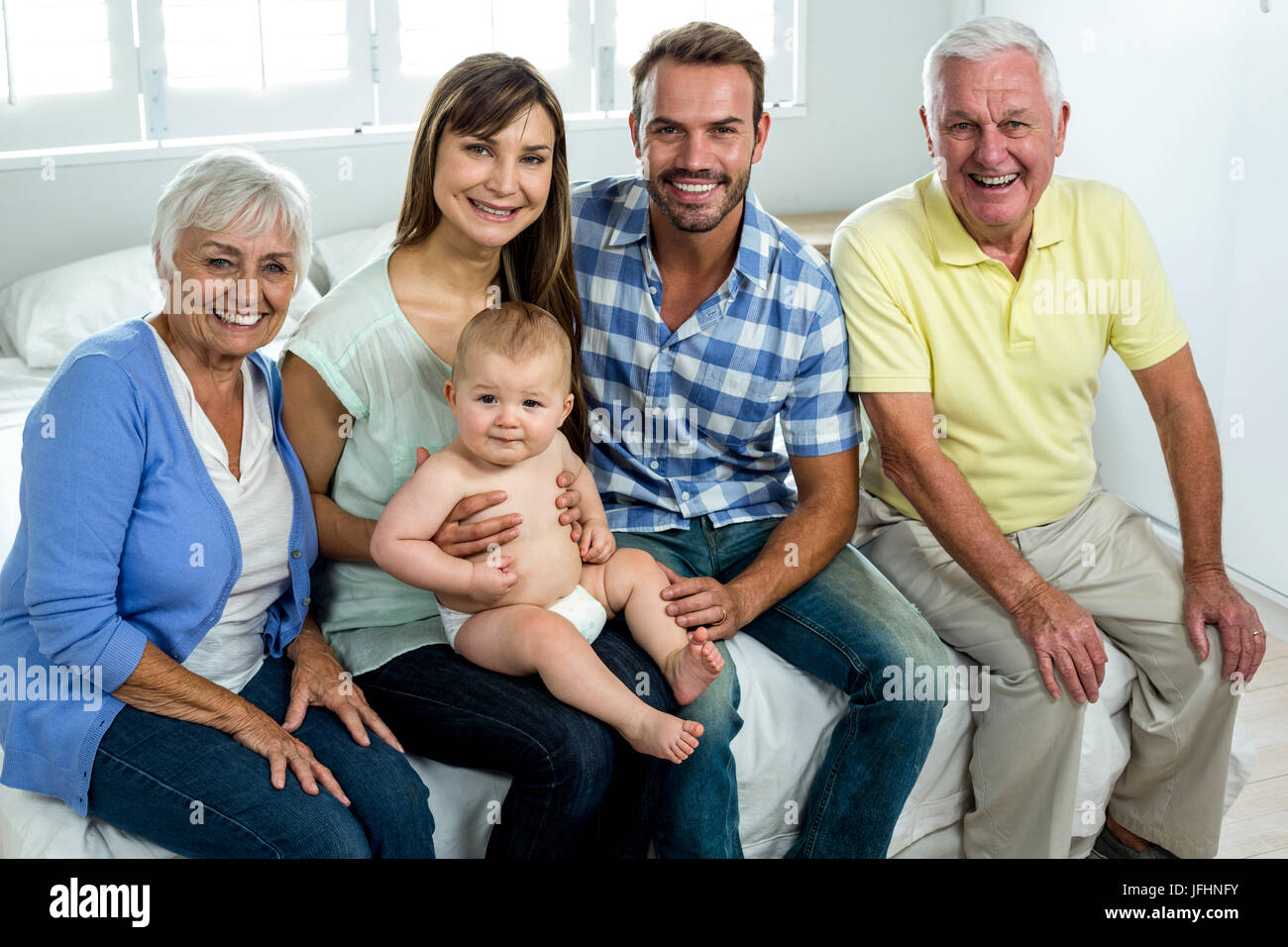 Happy multi-generation family sitting on bed at home Stock Photo - Alamy