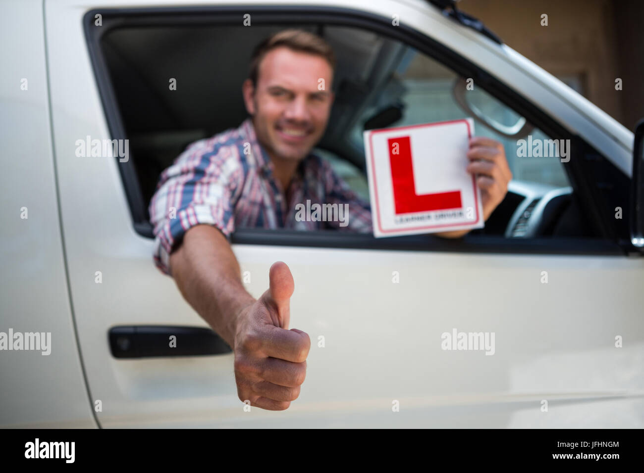 Young man gesturing thumbs up holding a learner driver sign Stock Photo ...