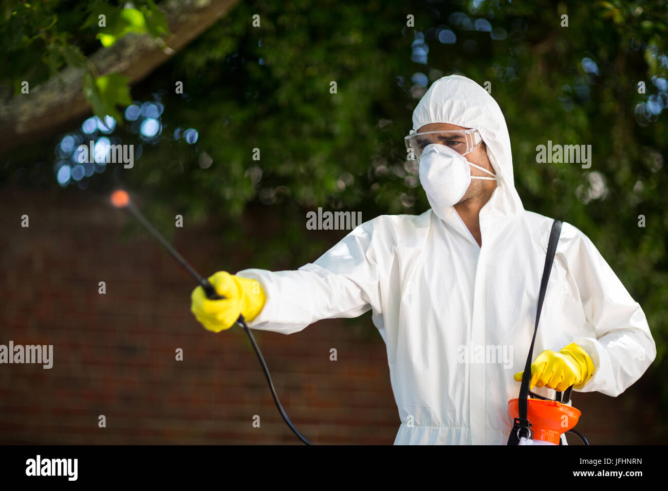 Man using insecticide while standing against tree Stock Photo - Alamy