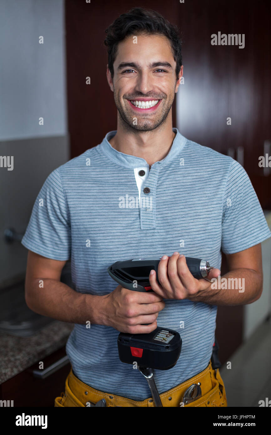 Portrait of cheerful man holding cordless hand drill Stock Photo - Alamy