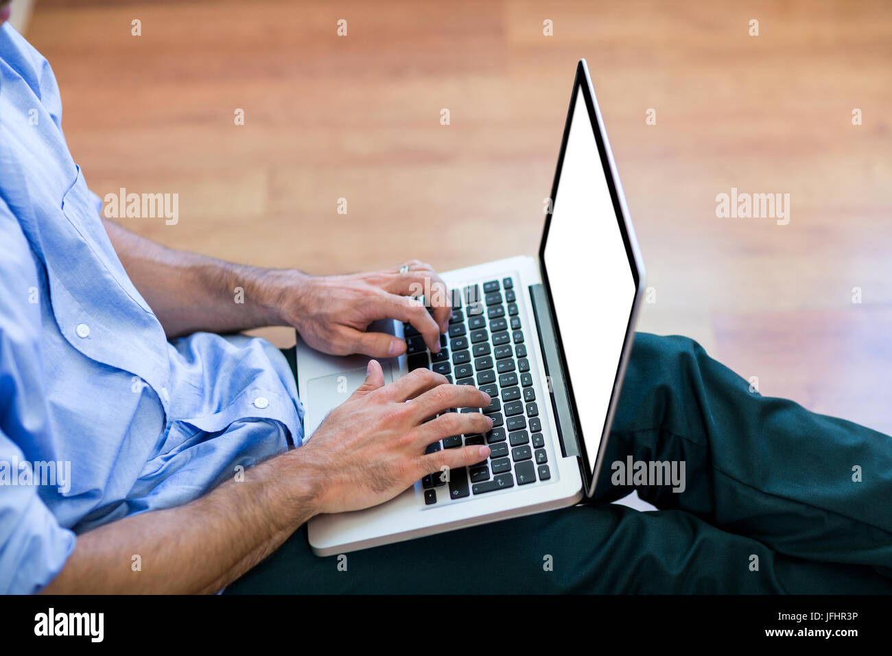 Mid-section of man sitting on floor and using laptop Stock Photo - Alamy